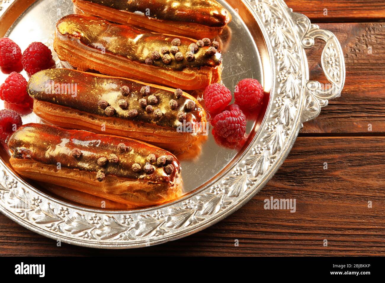 Delicious eclairs on silver plate, wooden background Stock Photo - Alamy