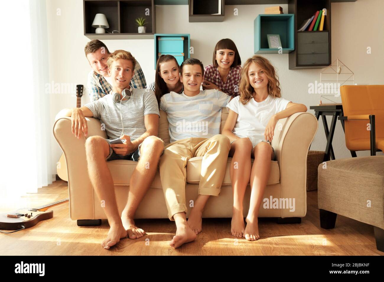 Happy friends sitting on couch at home Stock Photo - Alamy