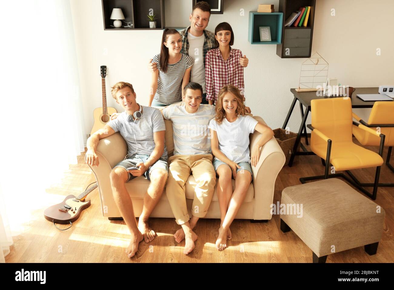 Happy friends sitting on couch at home Stock Photo - Alamy