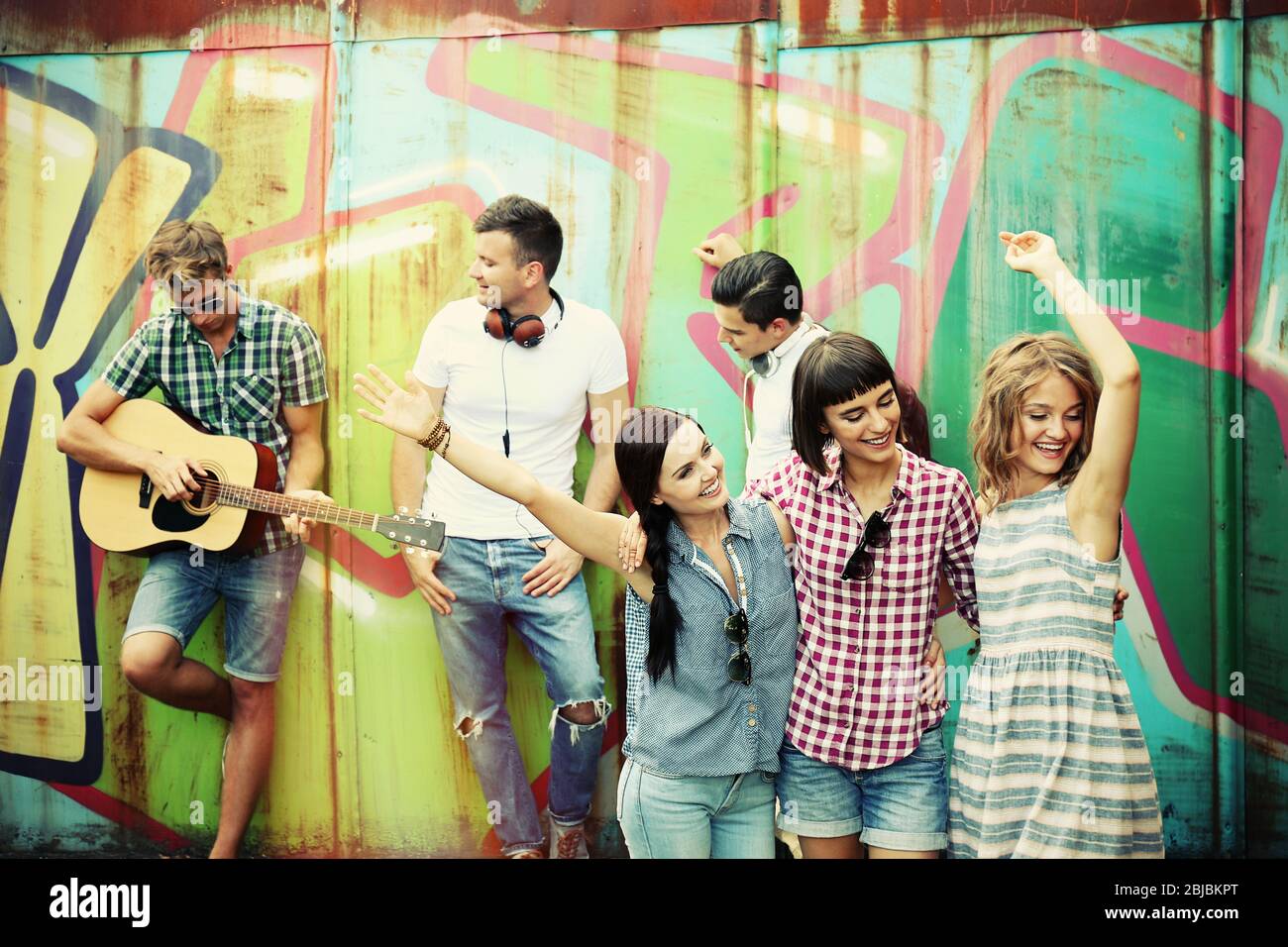 Happy friends listening to music on street Stock Photo - Alamy