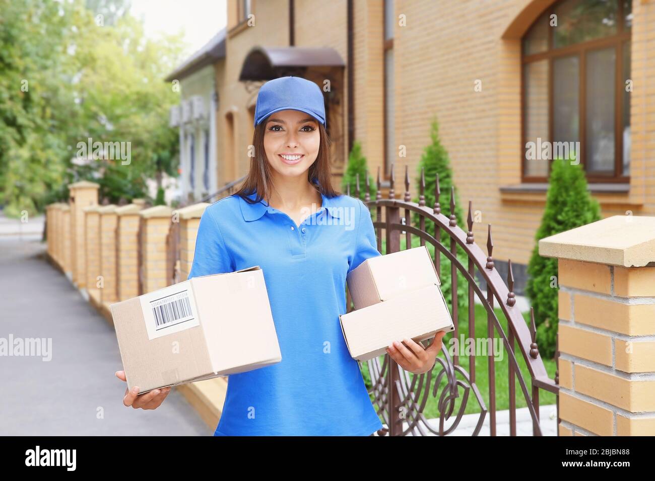Female courier in uniform delivering parcels outdoor Stock Photo - Alamy
