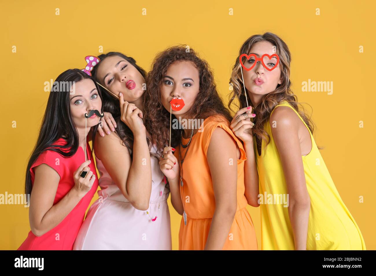 Happy girls on yellow wall background Stock Photo - Alamy