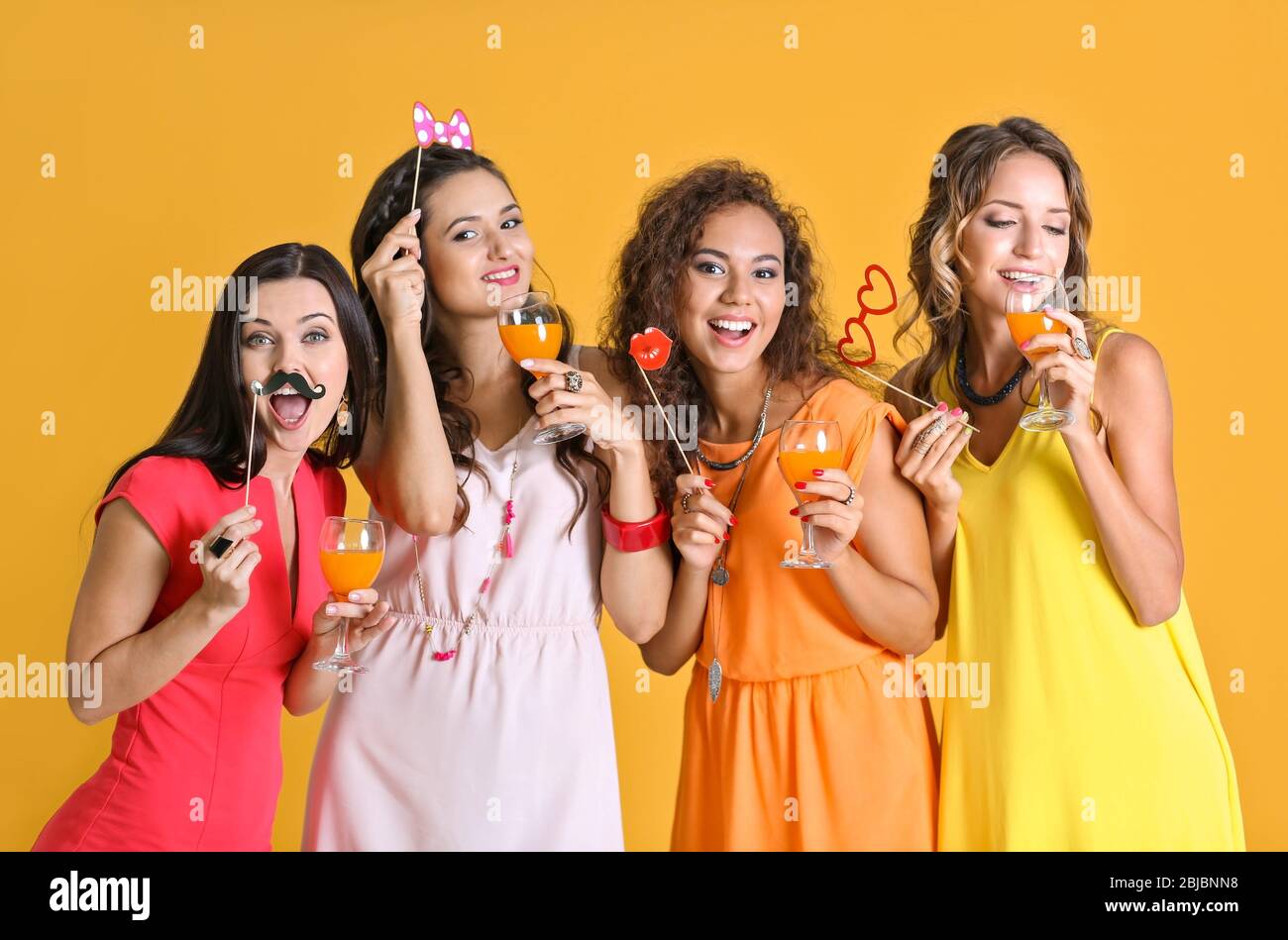 Beautiful girls with cocktails on yellow wall background Stock Photo ...