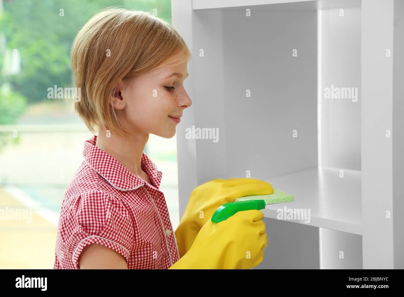 Small girl cleaning shelf with spray, indoor Stock Photo - Alamy