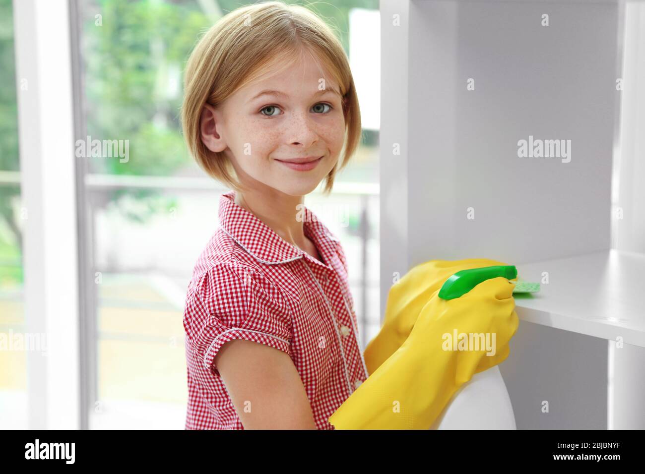 Small girl cleaning shelf with spray, indoor Stock Photo - Alamy