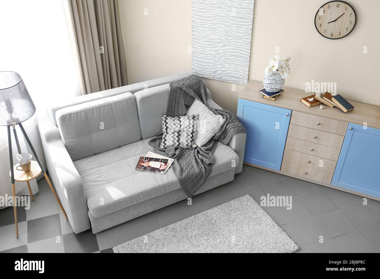 Modern interior with sofa, window and chest of drawers Stock Photo - Alamy