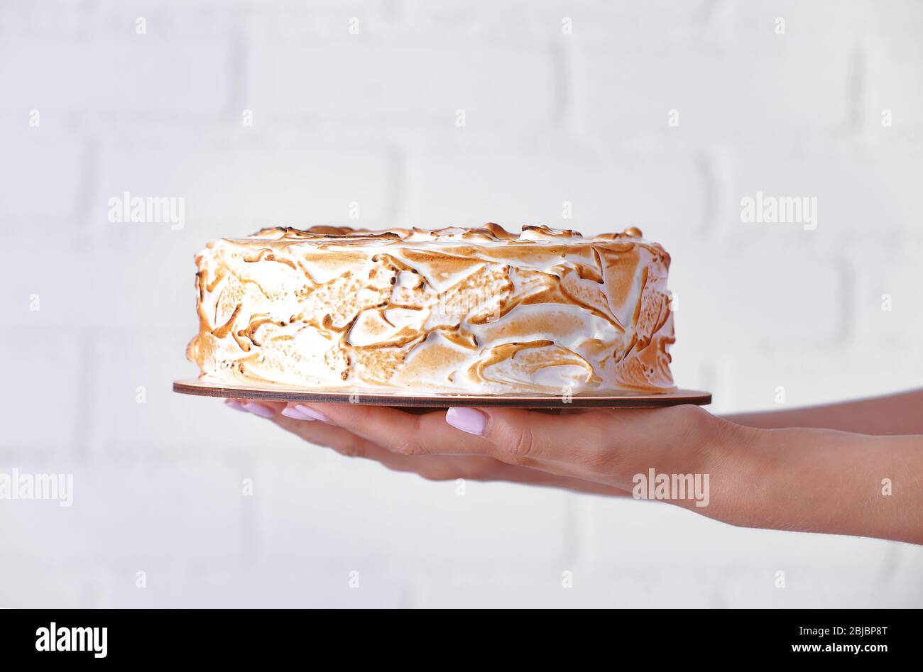 Female hands holding delicious cake on brick wall background Stock ...