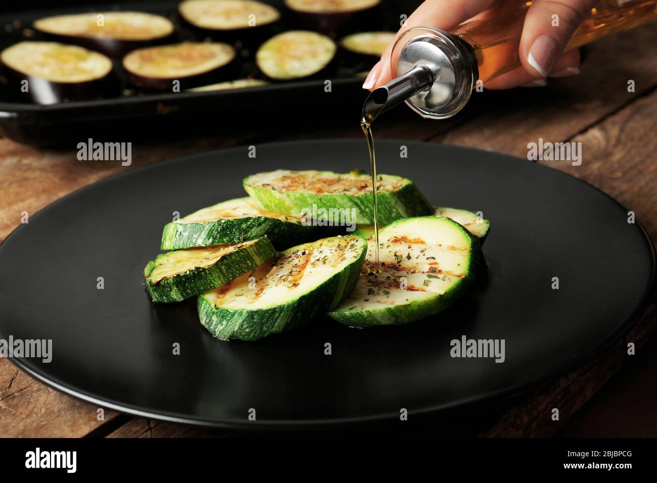 Female hand pouring oil over squash slices Stock Photo - Alamy