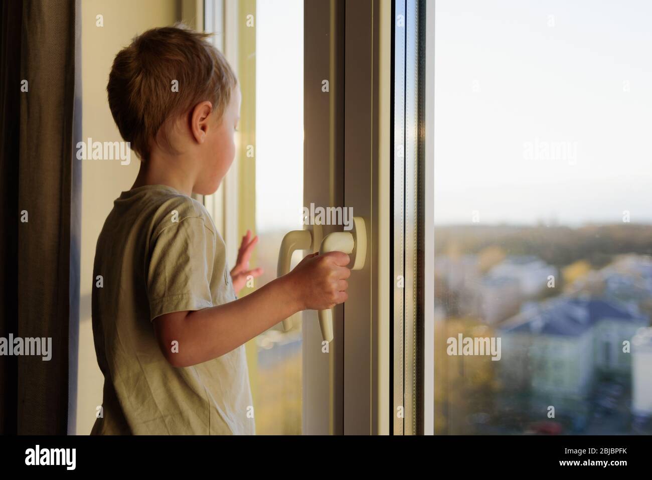 Boy looking through window to outside. Child opening window without ...