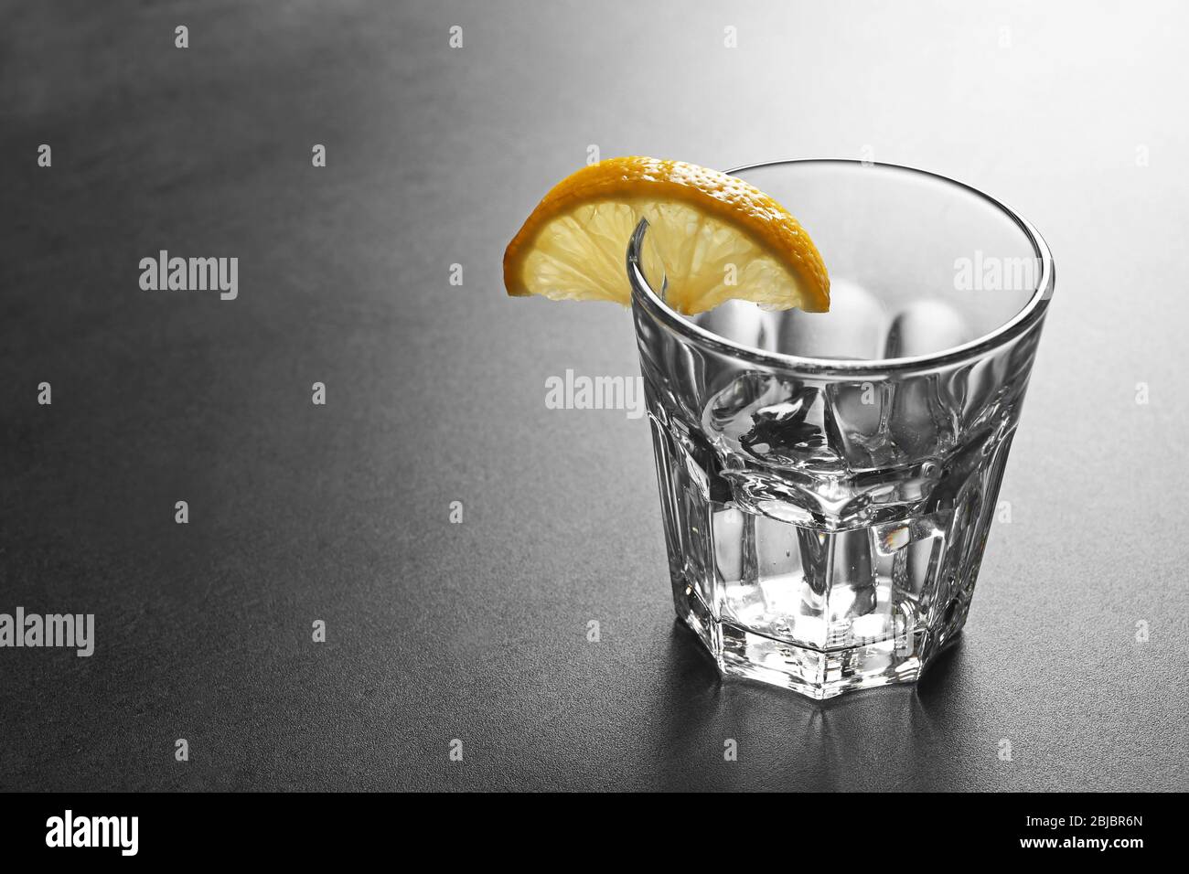 Glass of vodka with lemon and ice on grey textured background Stock ...