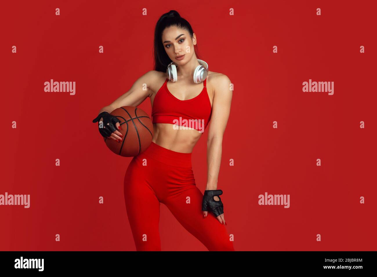 Beautiful young female athlete practicing in studio, monochrome red ...