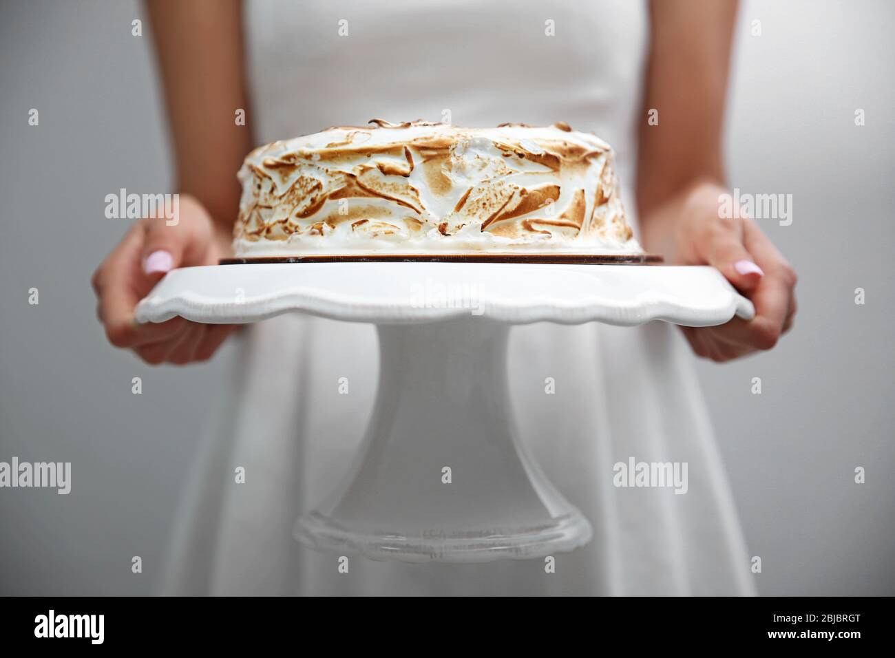 Woman holding birthday cake on white stand Stock Photo - Alamy