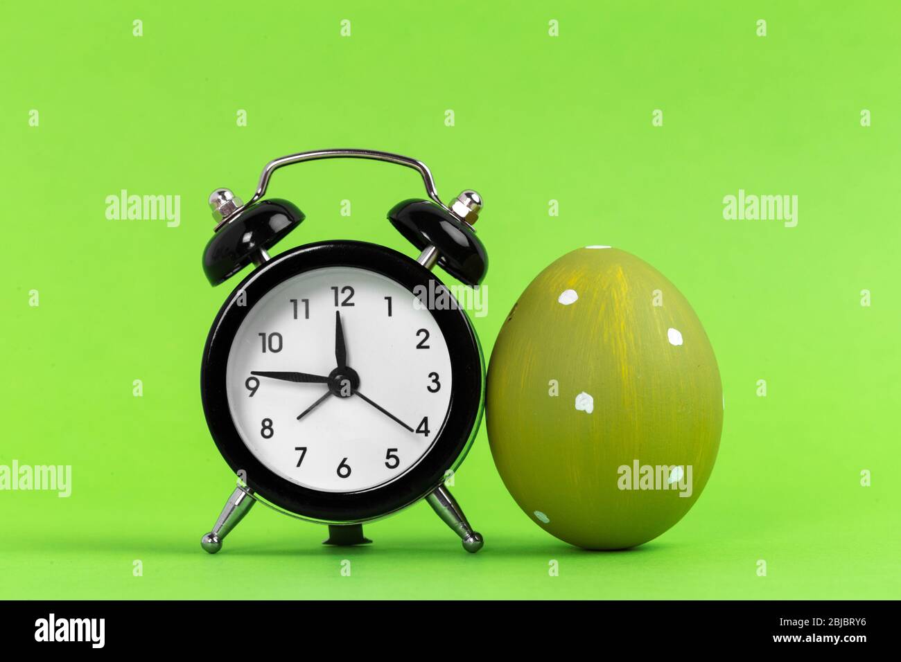 Easter alarm clock with colorful egg. Time to celebrate Stock Photo - Alamy