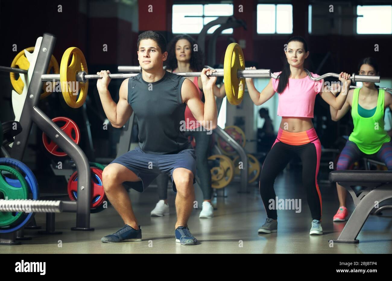 Group of young people training with barbell in gym Stock Photo - Alamy