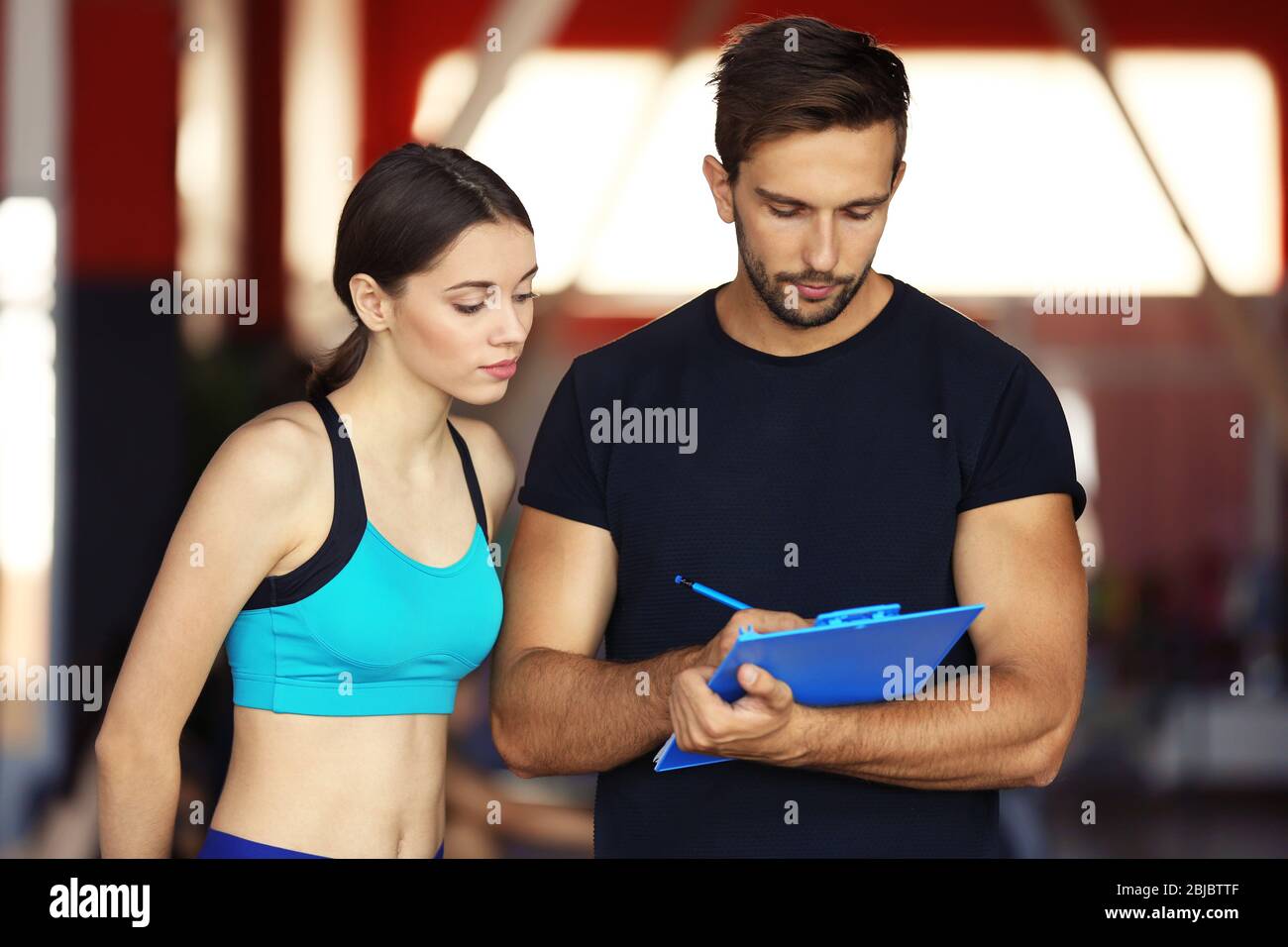Woman with personal trainer preparing training plan in gym Stock Photo ...