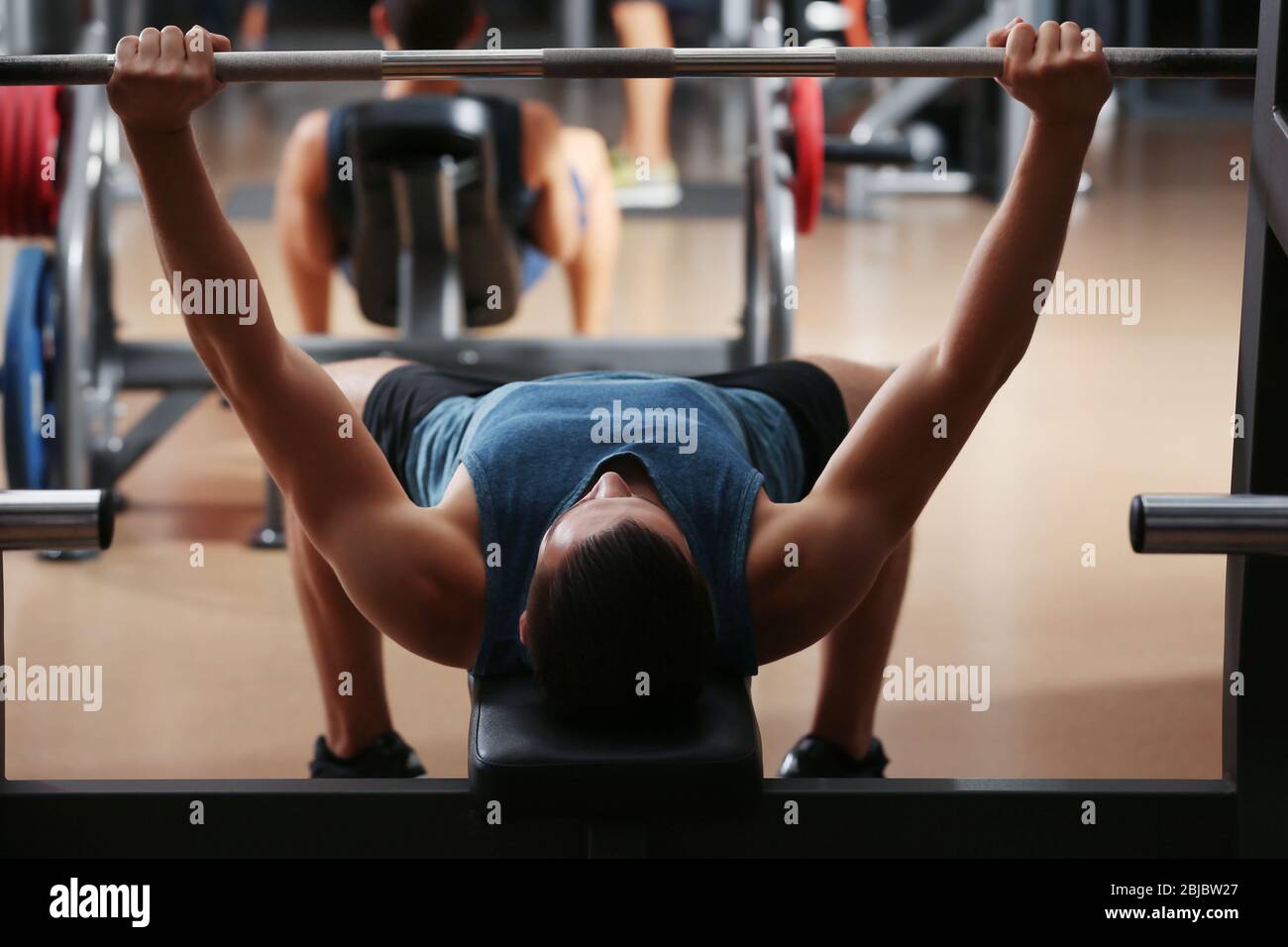 Athletic man training with barbell in gym Stock Photo - Alamy