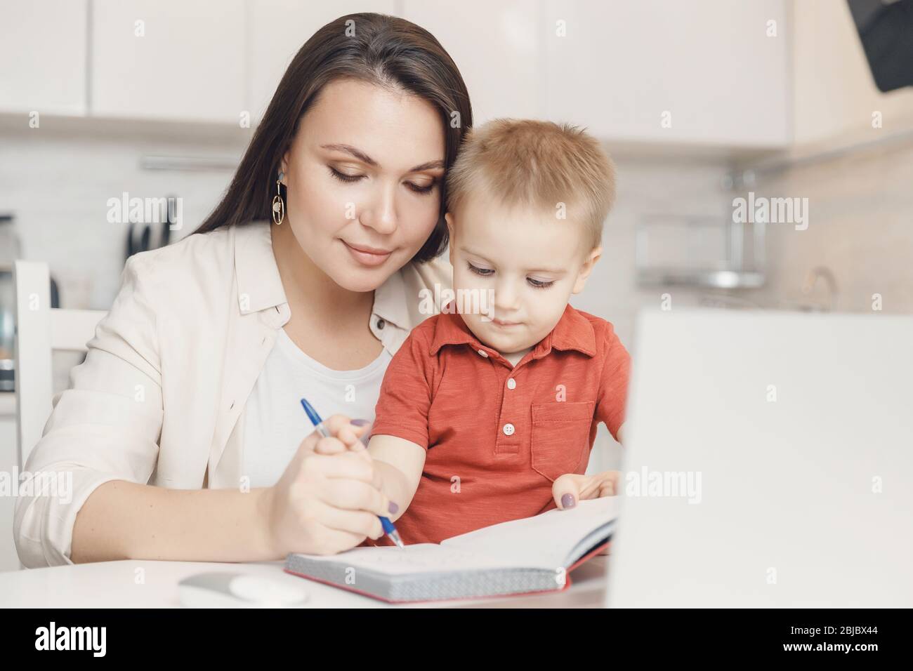 Mother teaching her kid son how to write pen. concept Online learning ...