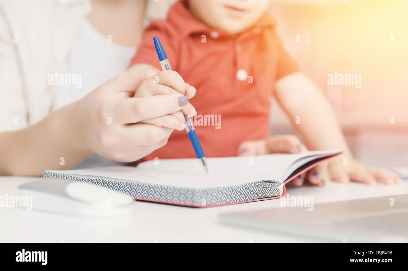 Mother teaching her kid son how to write pen. concept Online learning ...