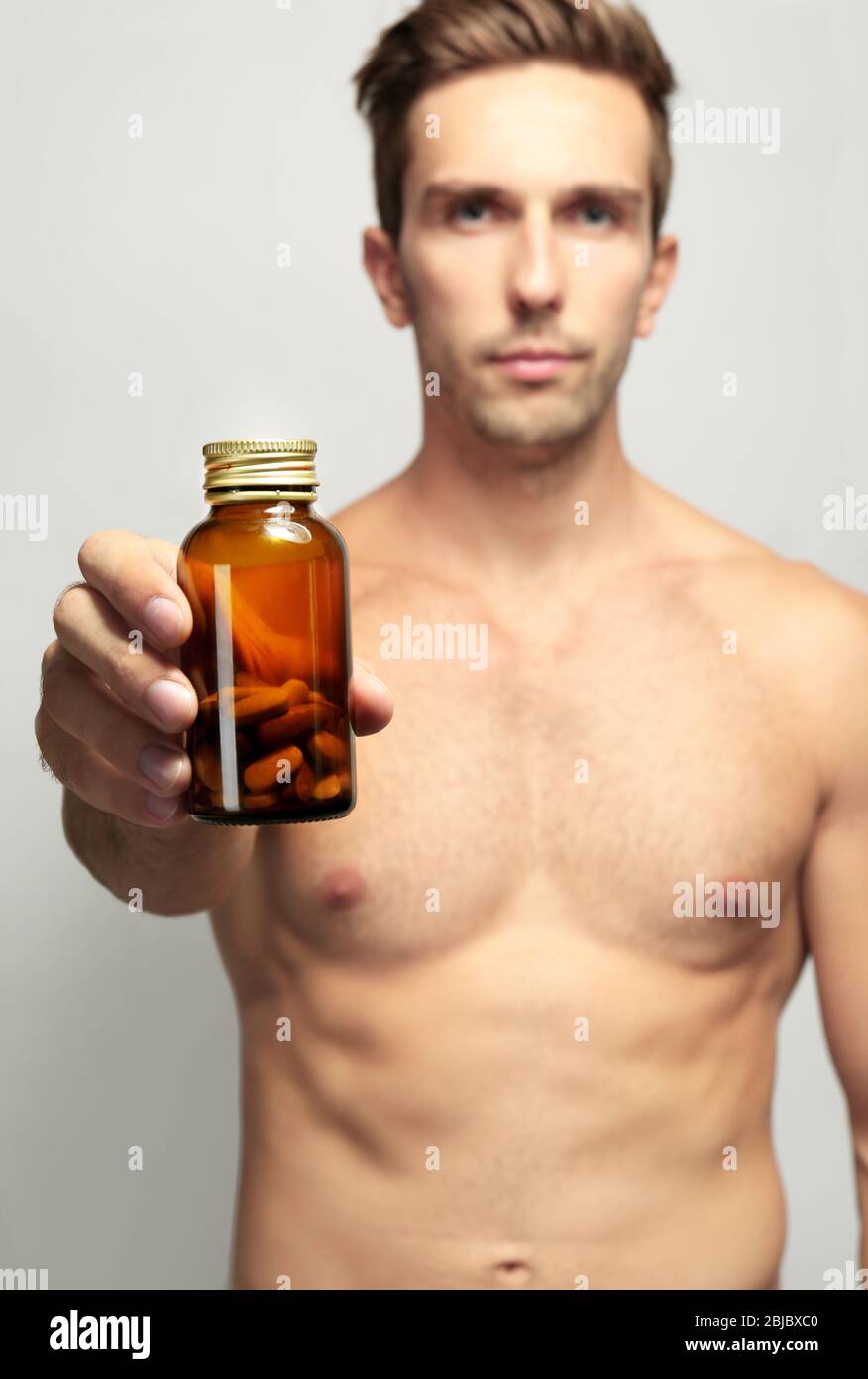 Muscular man holding drugs in bottle, closeup Stock Photo - Alamy