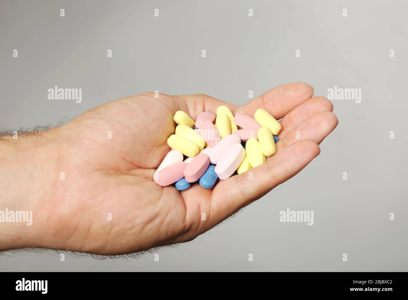 Male hand holding drugs on color background Stock Photo - Alamy