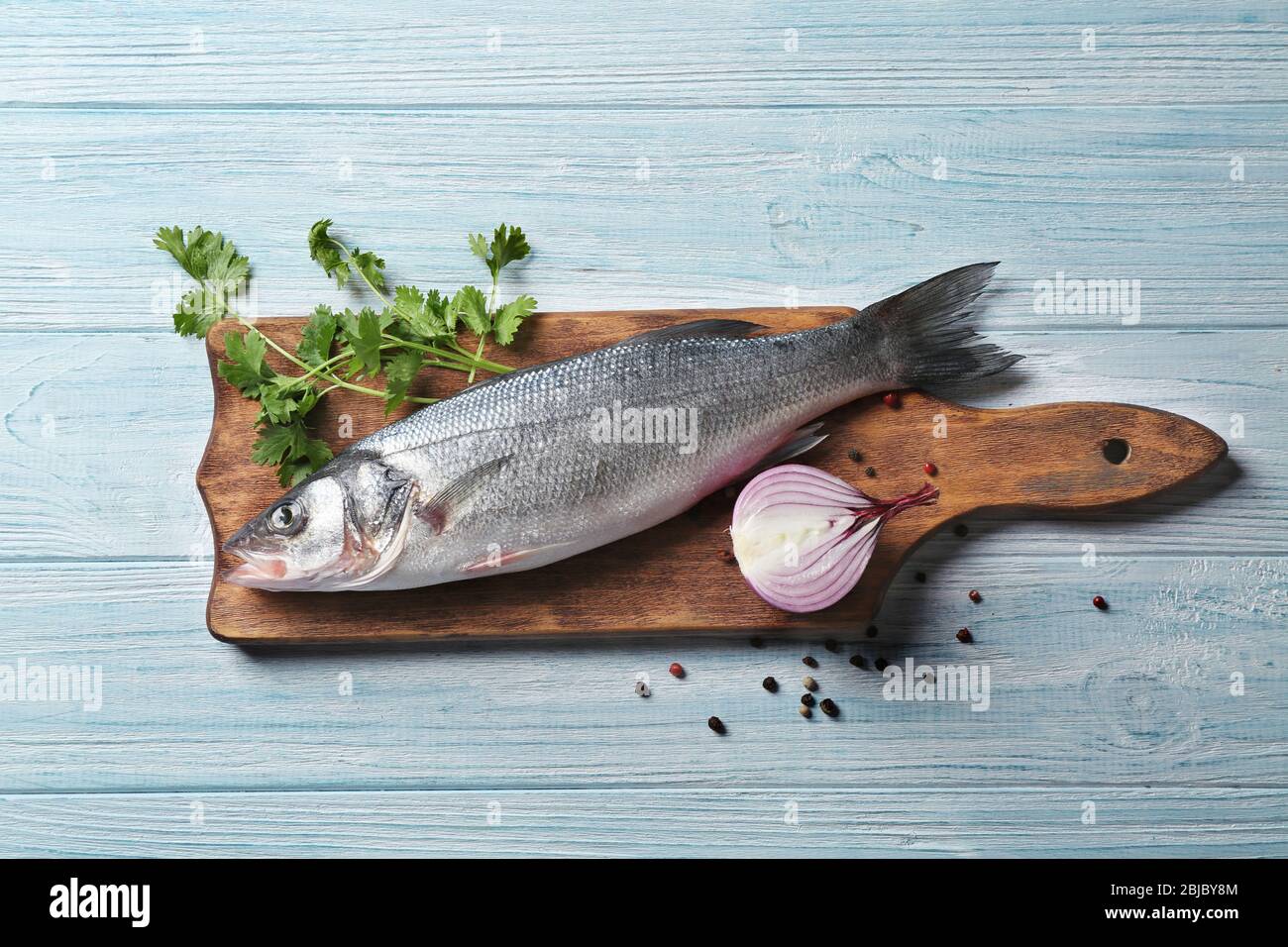 Raw fish with onion and parsley on cutting board Stock Photo - Alamy