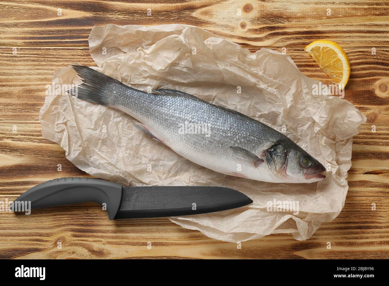 Raw fish with knife on wooden table Stock Photo - Alamy