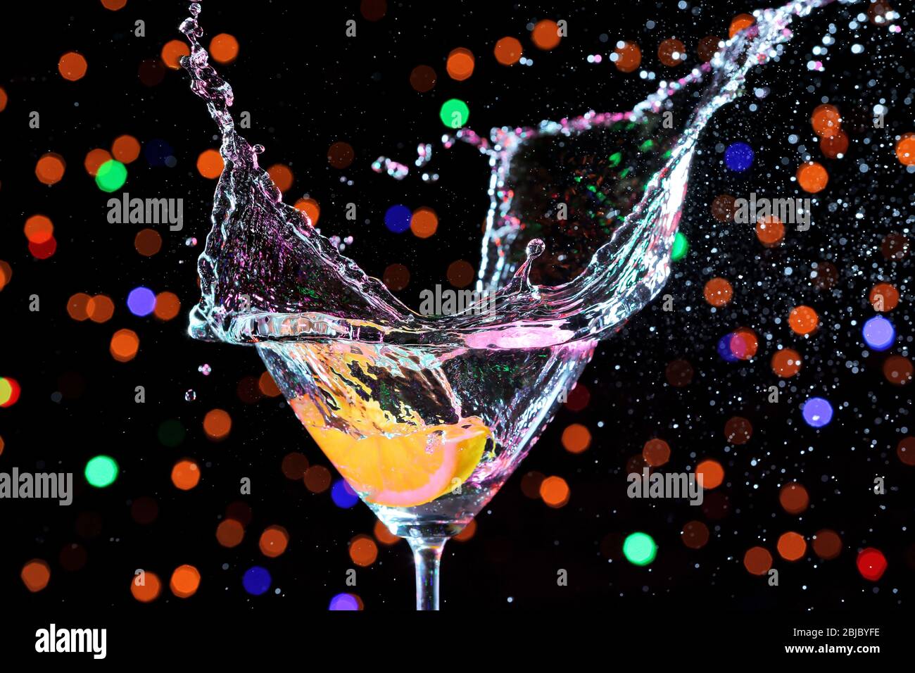 Colorful cocktail with splash on blurred lights background Stock Photo ...