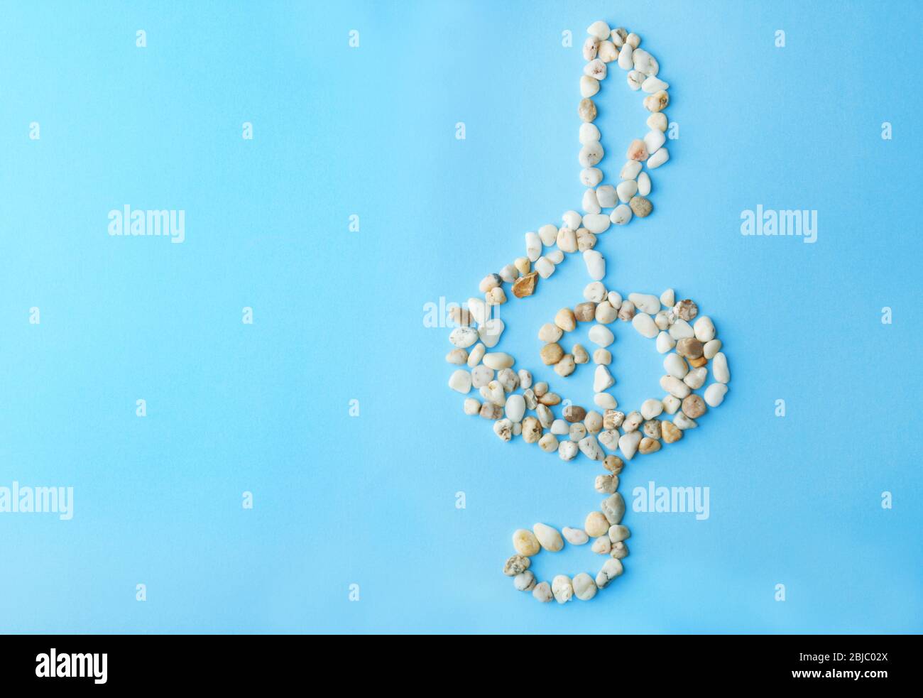 Treble clef made of small stones on blue background, closeup Stock ...