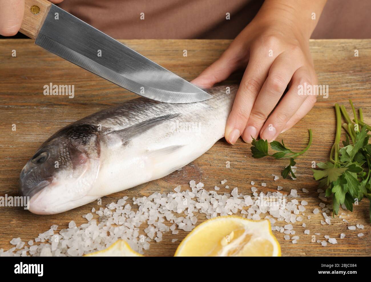Woman cooking raw fish on kitchen Stock Photo - Alamy