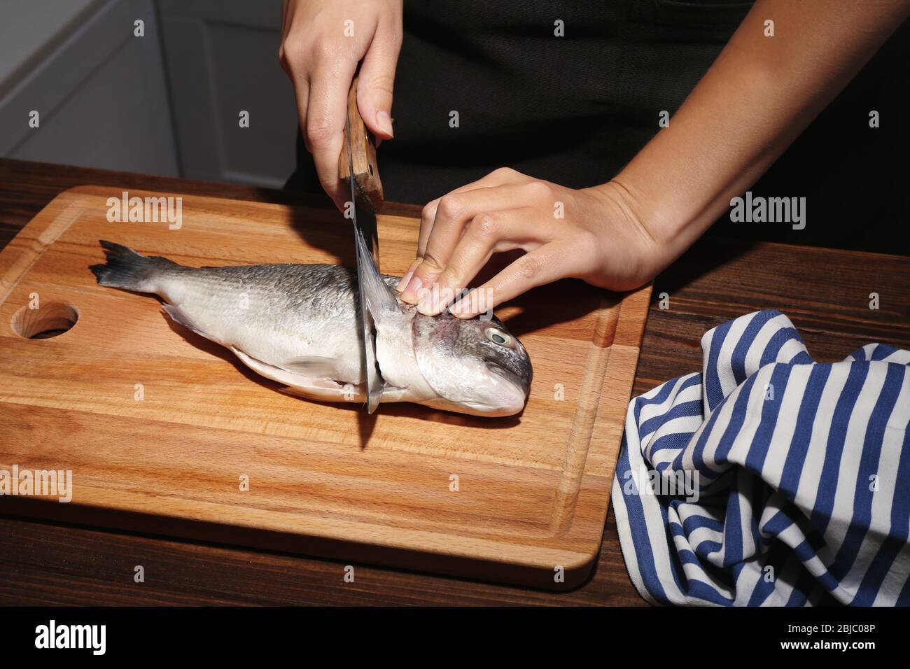 Woman cooking raw fish on kitchen Stock Photo - Alamy