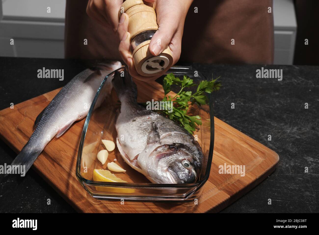 Woman cooking raw fish on kitchen Stock Photo - Alamy
