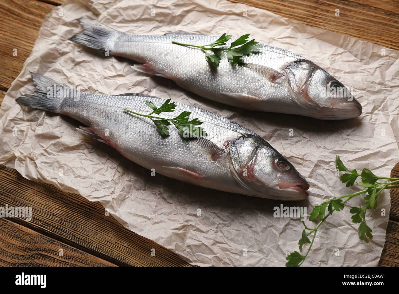 Raw fish with parsley on kitchen table Stock Photo - Alamy