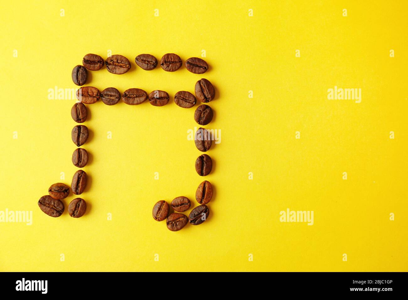 Musical note made of coffee beans on yellow background Stock Photo - Alamy