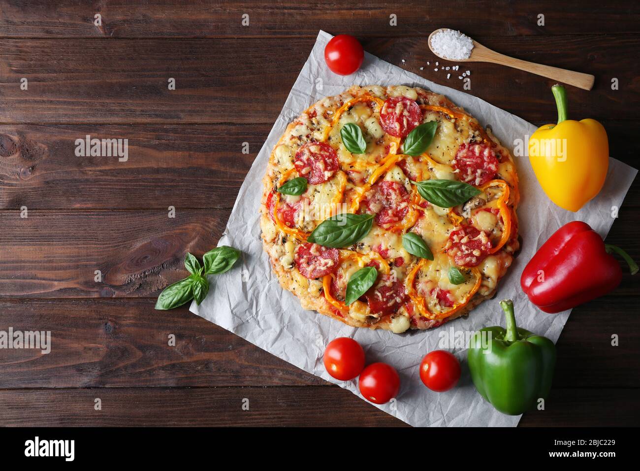 Composition of tasty pizza, vegetables and spoon on wooden background ...