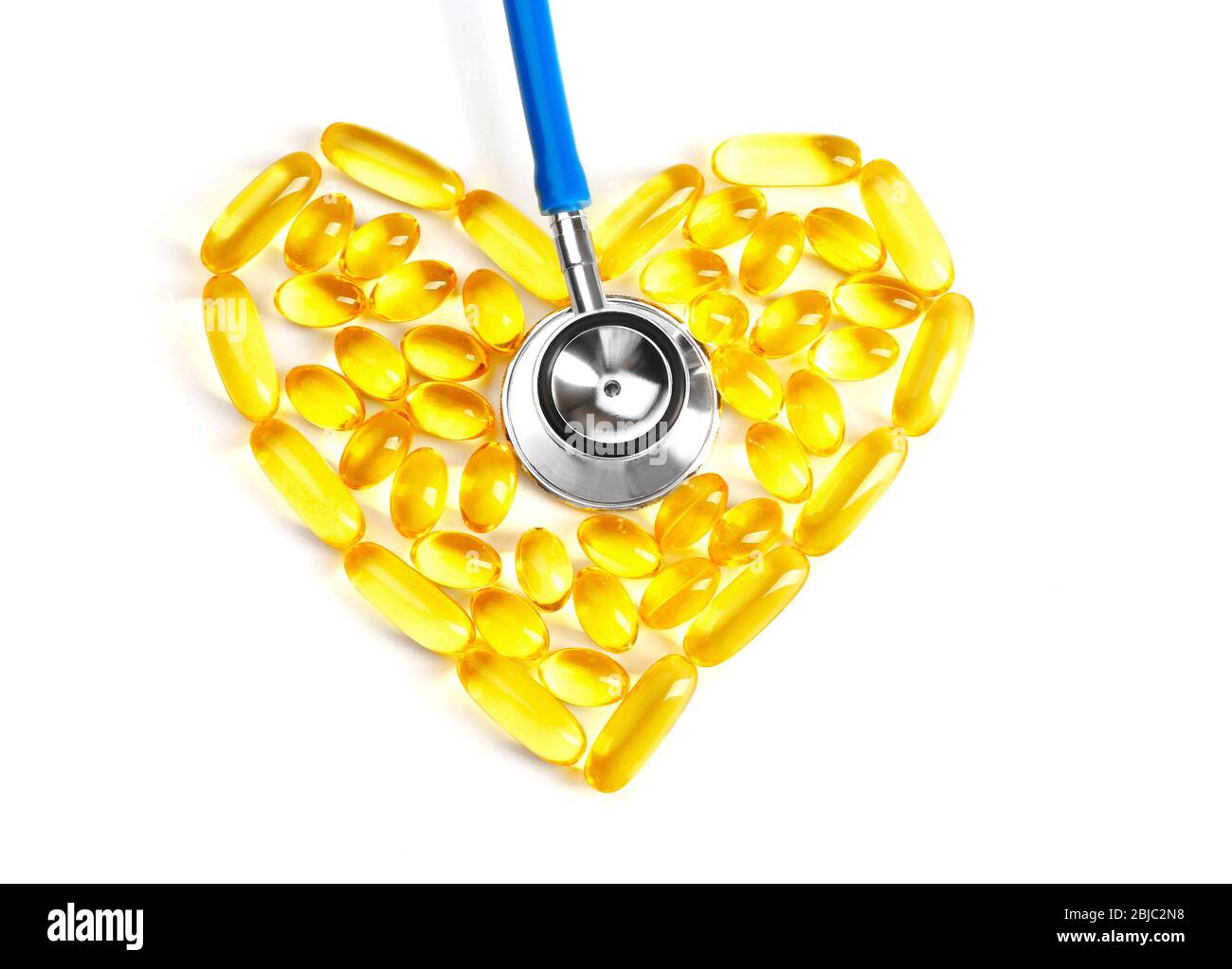 Cod liver oil capsules in heart shape with stethoscope on white ...