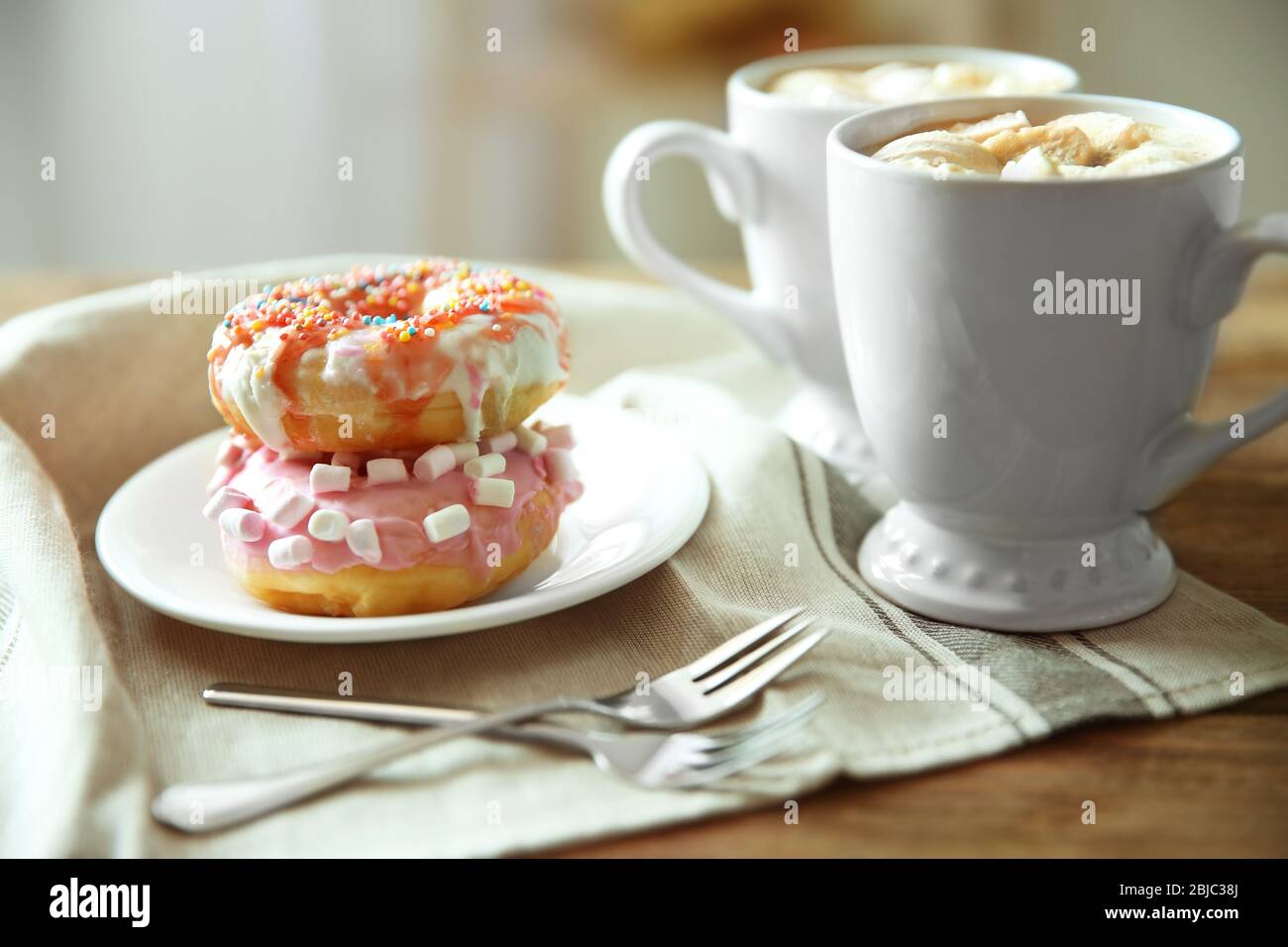 Plate with delicious doughnuts and cups of coffee on the table Stock ...