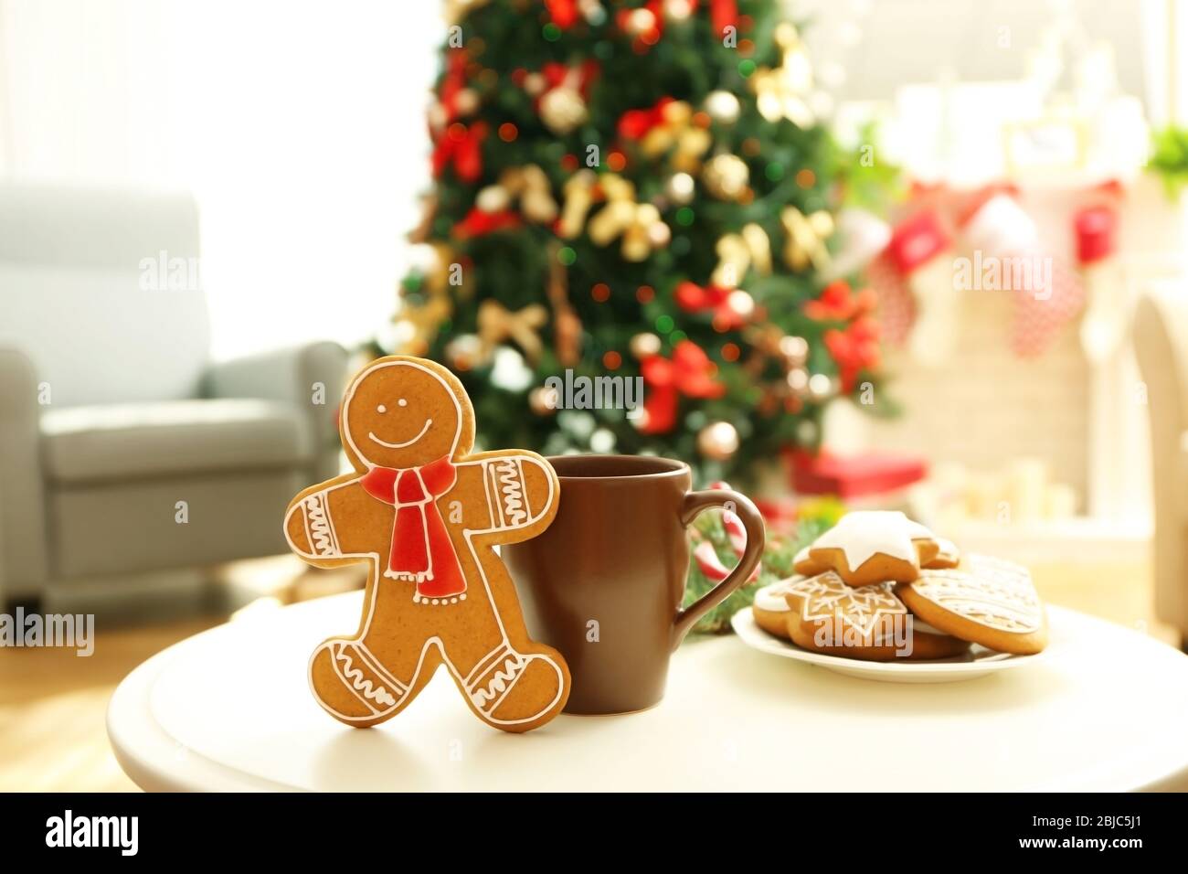 Gingerbread man, cup and plate with cookies on table against blurred ...