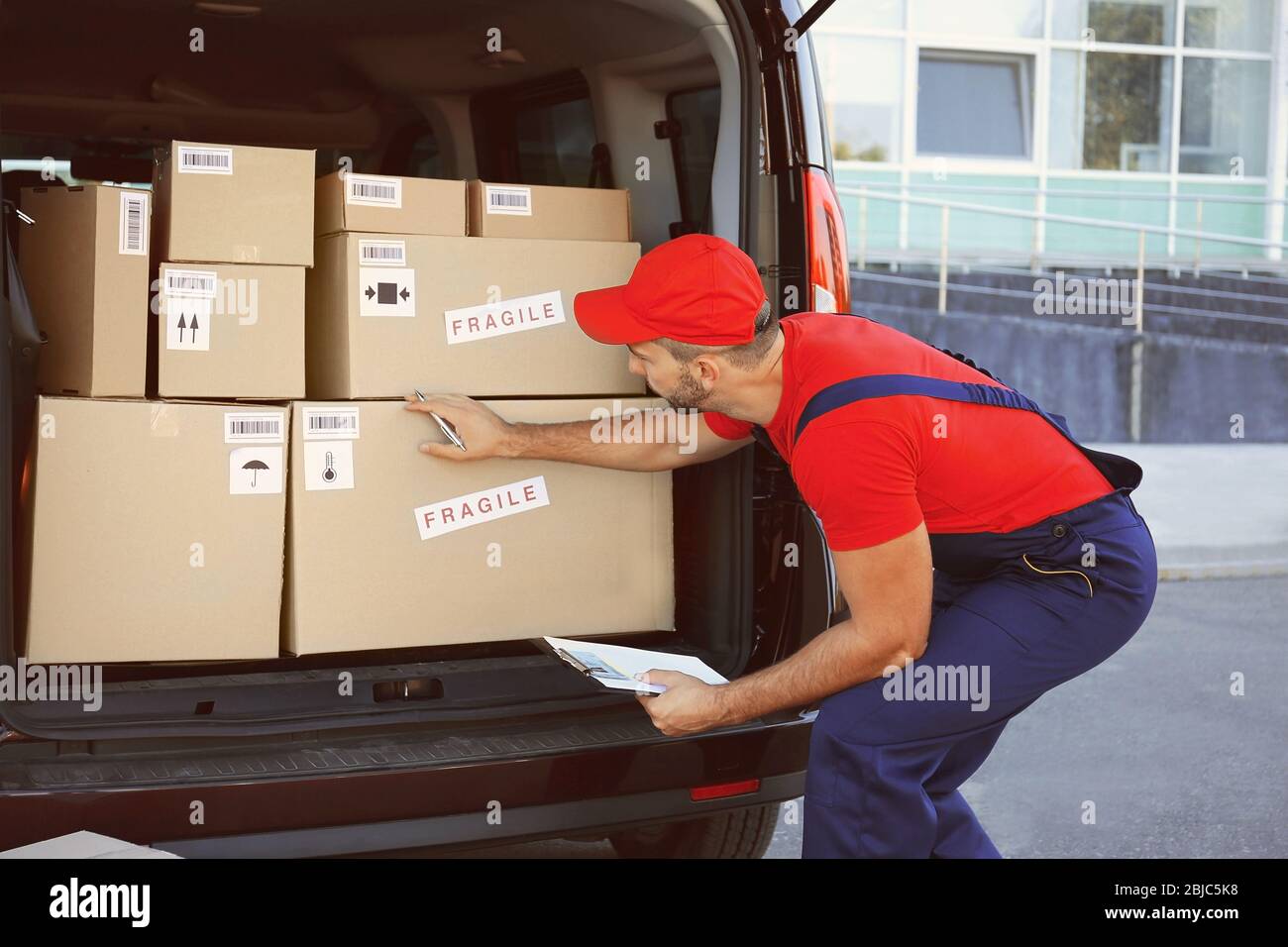 Delivery man checking packages Stock Photo - Alamy