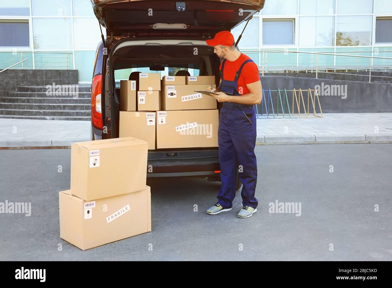 Delivery man checking packages Stock Photo - Alamy