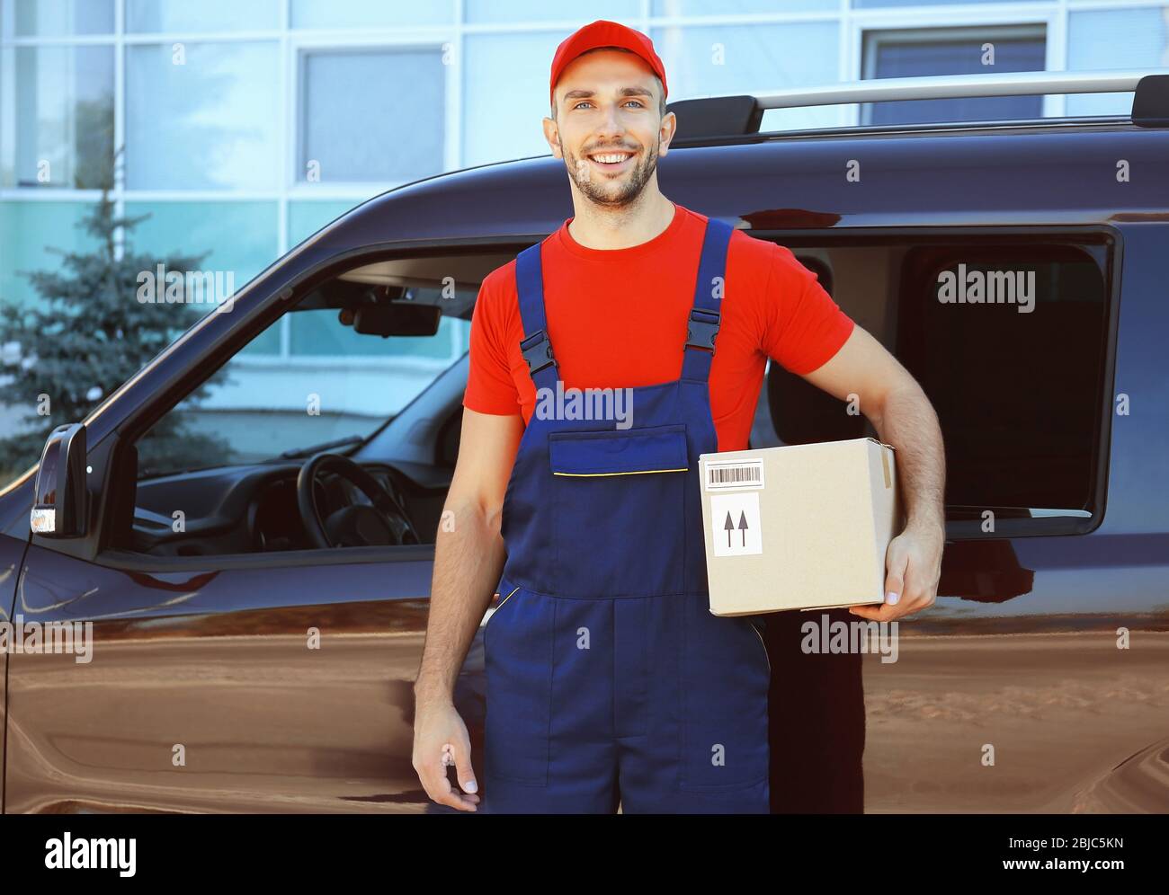 Delivery man holding package Stock Photo - Alamy