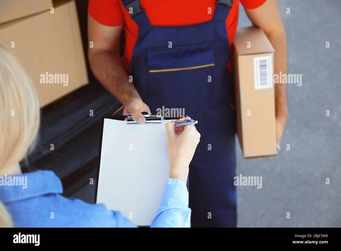 Woman receiving parcel from delivery man Stock Photo - Alamy
