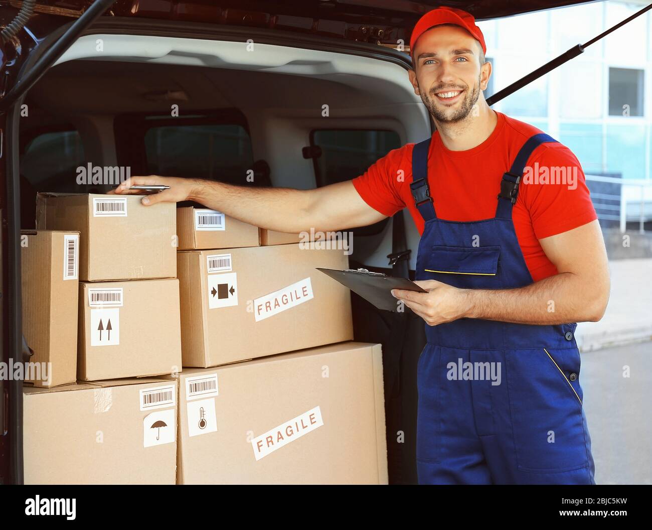 Delivery man checking packages Stock Photo - Alamy