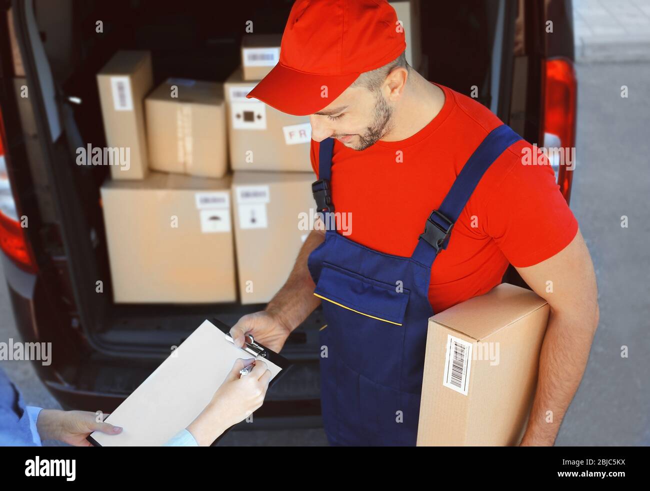 Woman receiving parcel from delivery man Stock Photo - Alamy