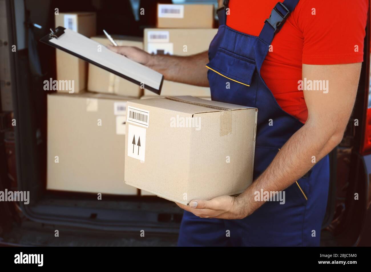 Delivery man checking packages Stock Photo - Alamy