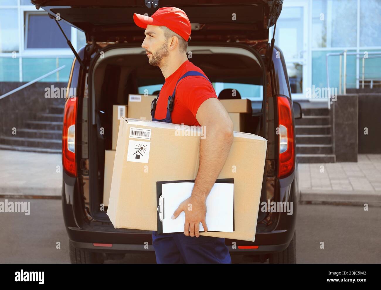 Delivery man holding package Stock Photo - Alamy