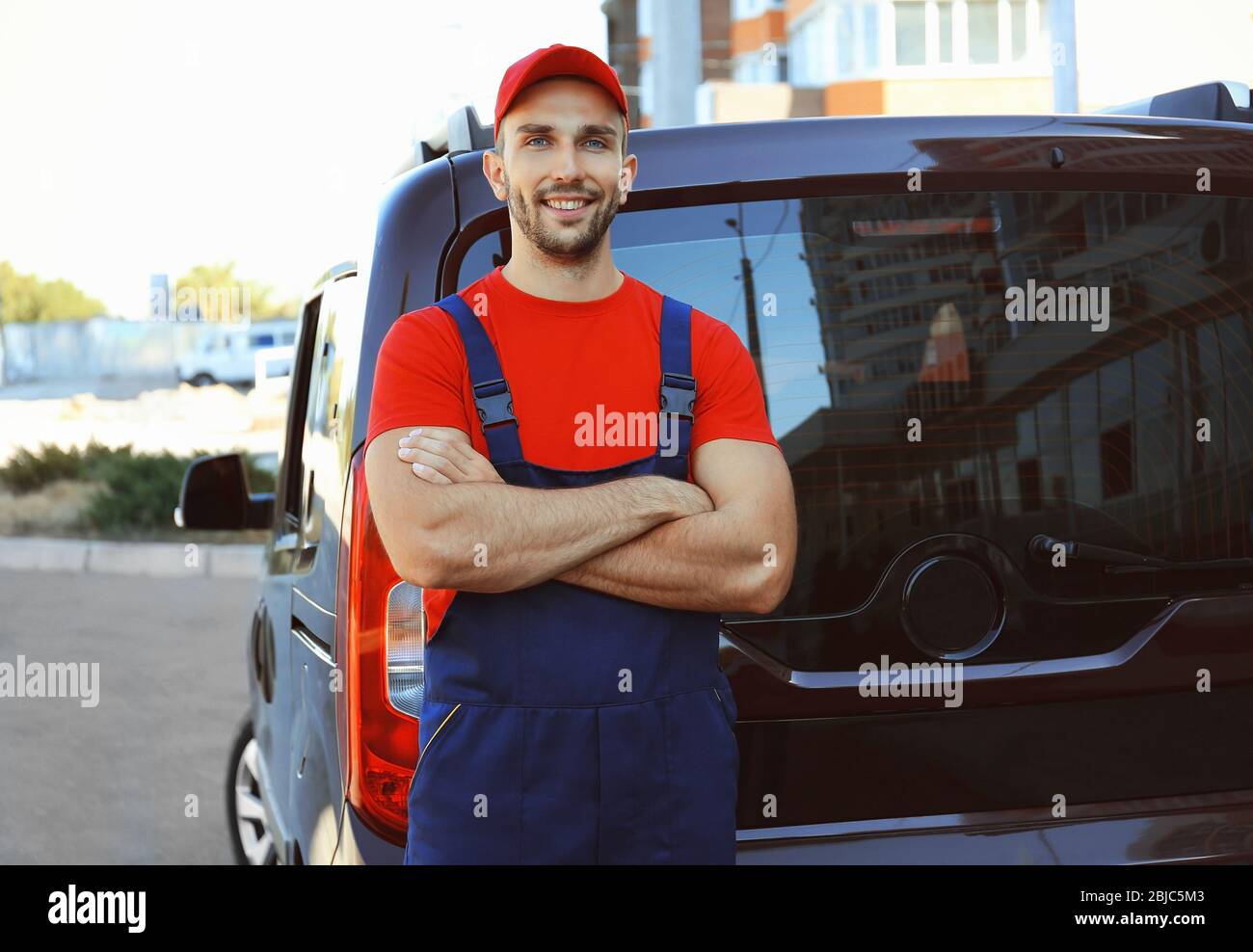 Delivery man standing beside car Stock Photo - Alamy
