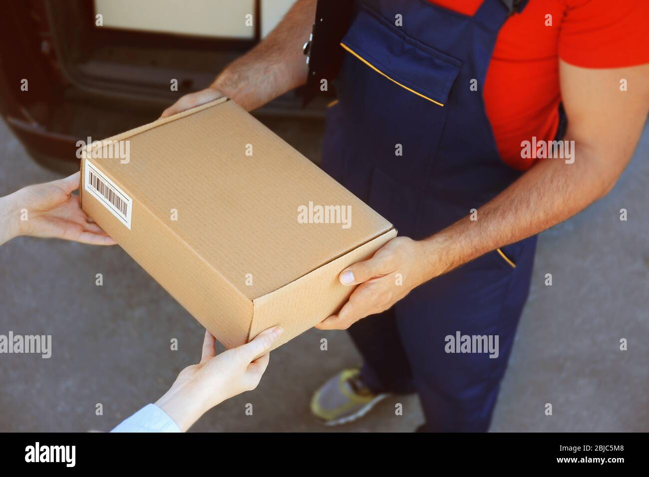 Woman receiving parcel from delivery man Stock Photo - Alamy