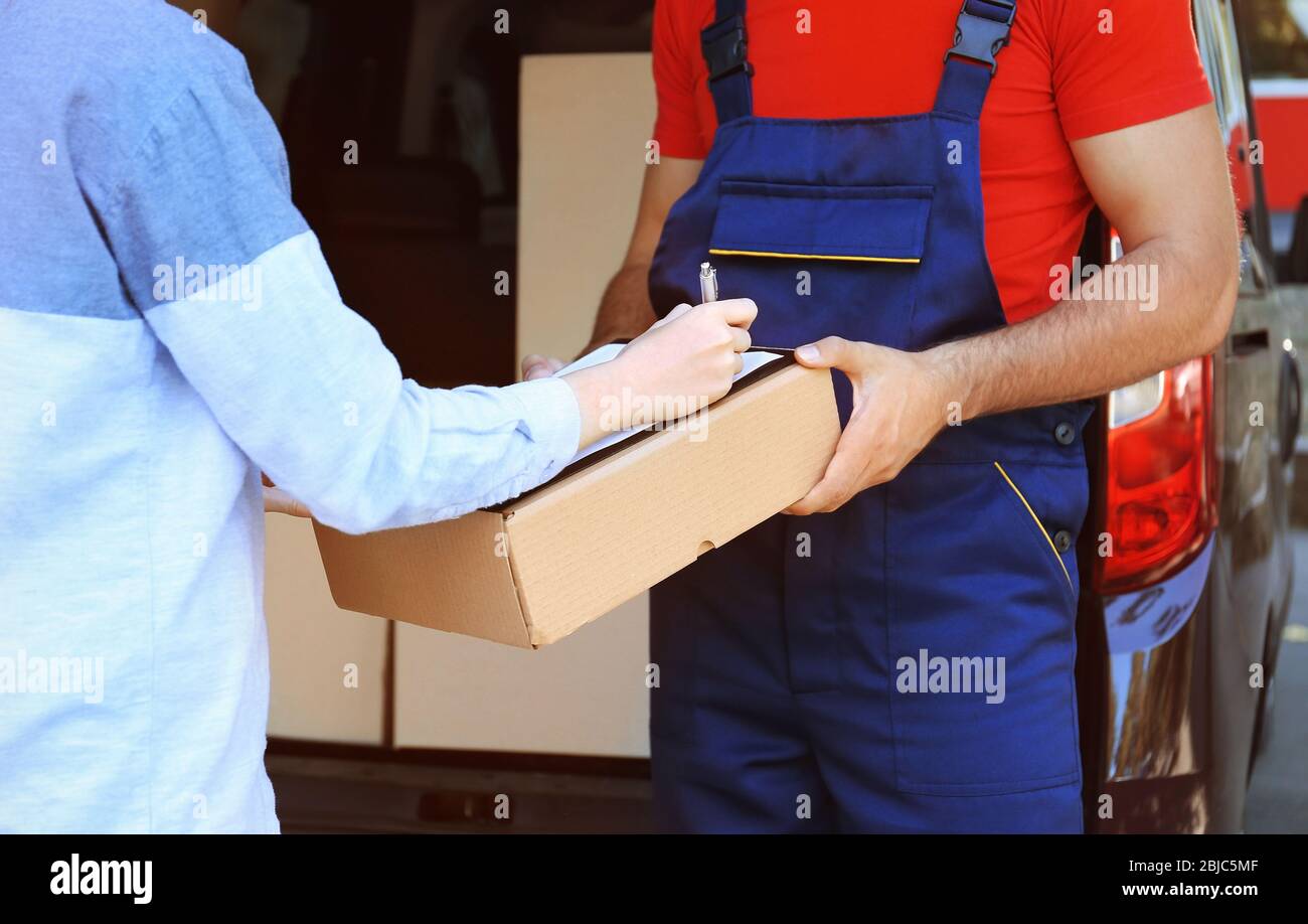 Woman receiving parcel from delivery man Stock Photo - Alamy