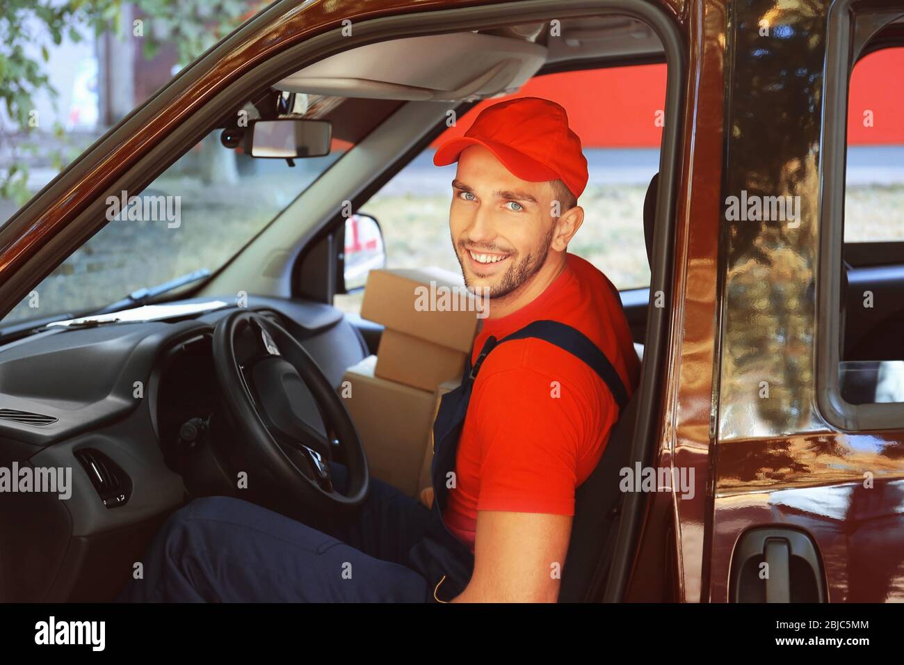 Delivery man with parcels in car Stock Photo - Alamy