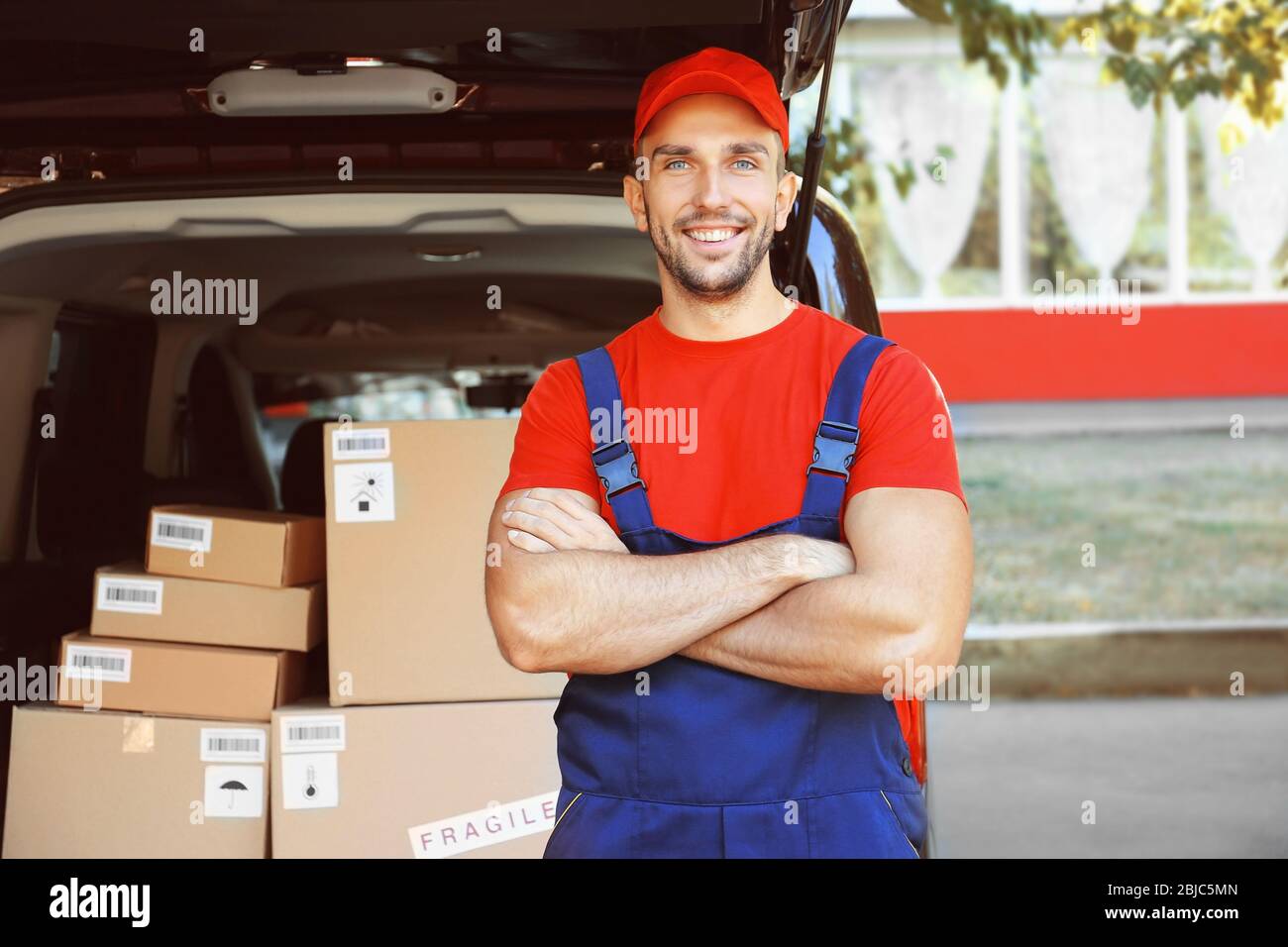Delivery man standing near car Stock Photo - Alamy